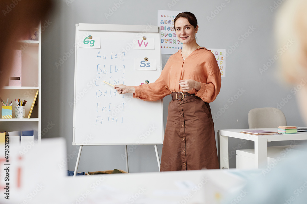 Portrait of young English teacher pointing at whiteboard with English ...