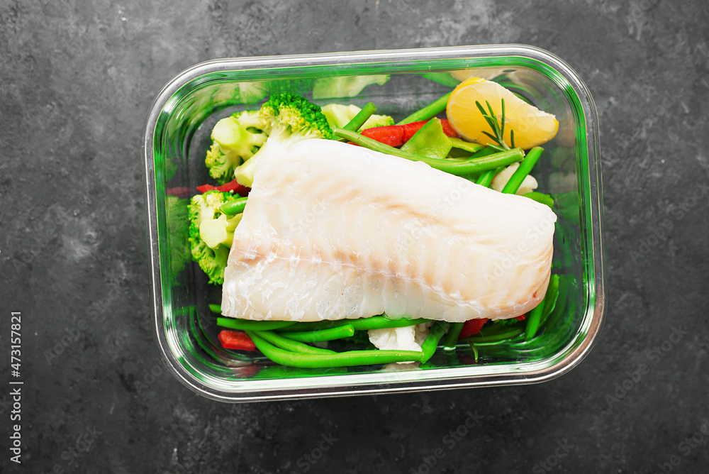 Foto de White cod fish fillet box. Fresh vegetables with a slice of cod ...