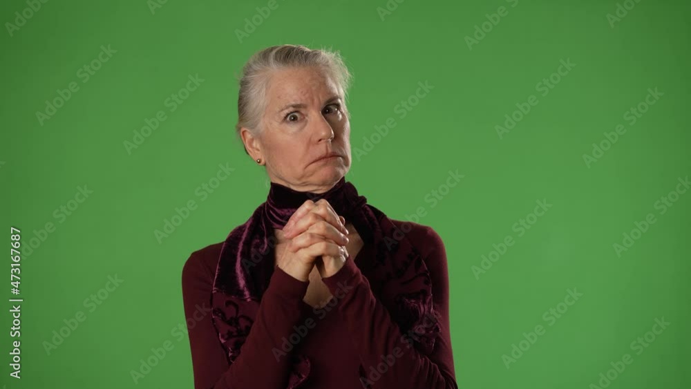 Portrait of surpised mature woman in her 50s looking at camera on green ...
