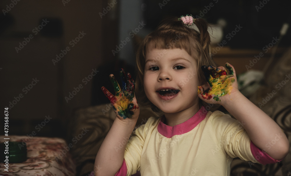 Cute happy smiling little child shows her hand palm colored by fingers ...