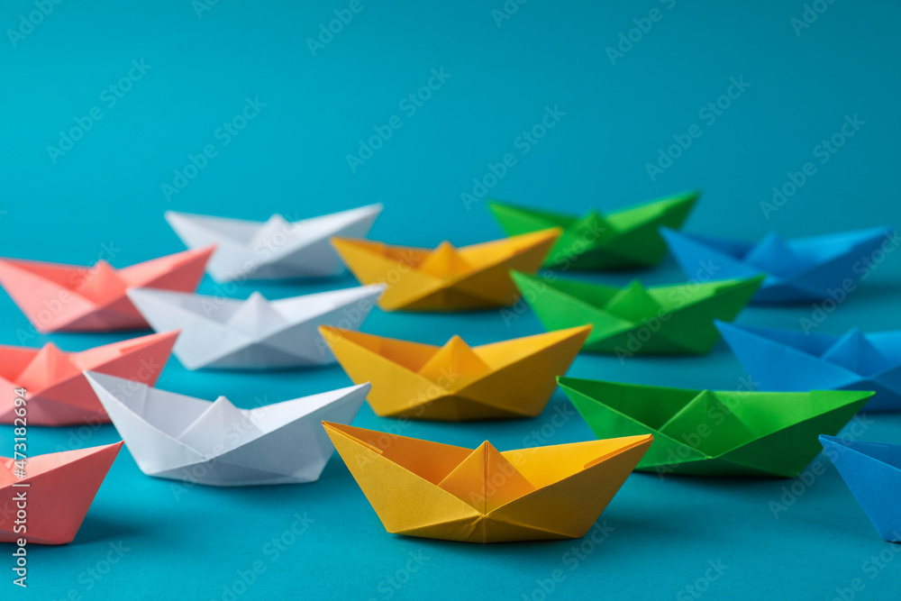 Many colorful handmade paper boats on light blue background. Origami ...