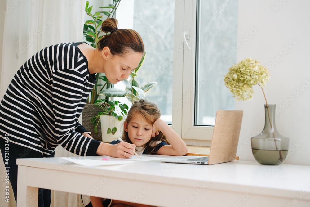 Mom helping little girl to draw. She's standing over the table, drawing ...