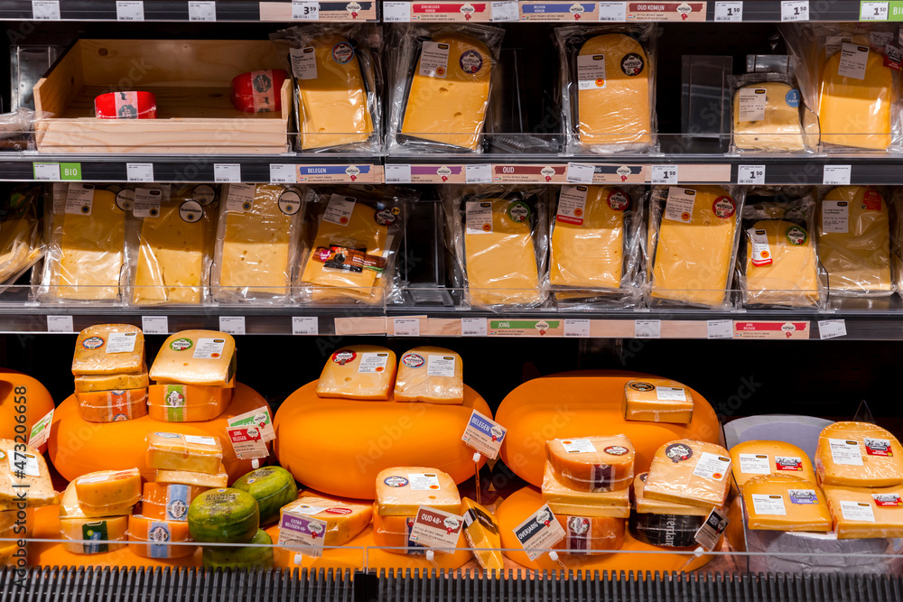 Different types of Dutch cheese wrapped and stacked in a grocery shop ...