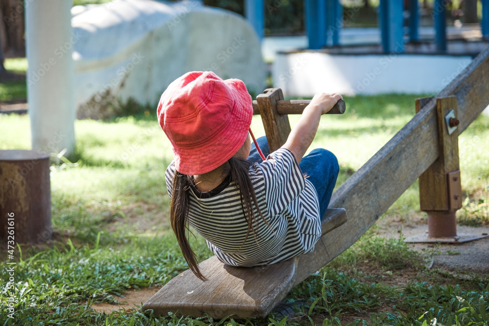 Active little girl playing on a seesaw in the outdoor playground. Happy ...