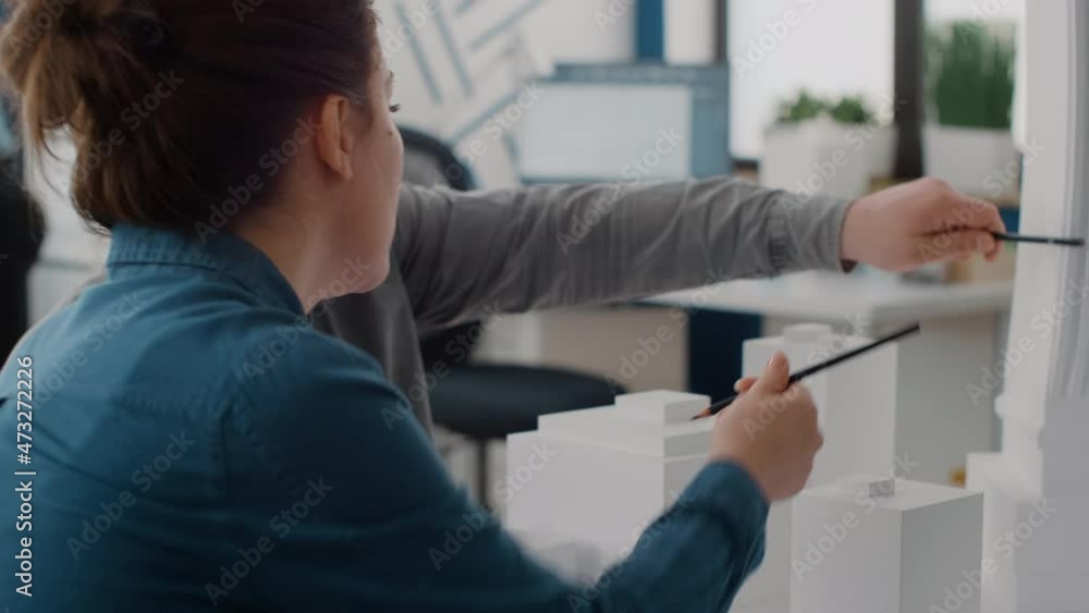 Close Up Of Man And Woman Talking About Maquette Design Analyzing Blueprints Plans On Table