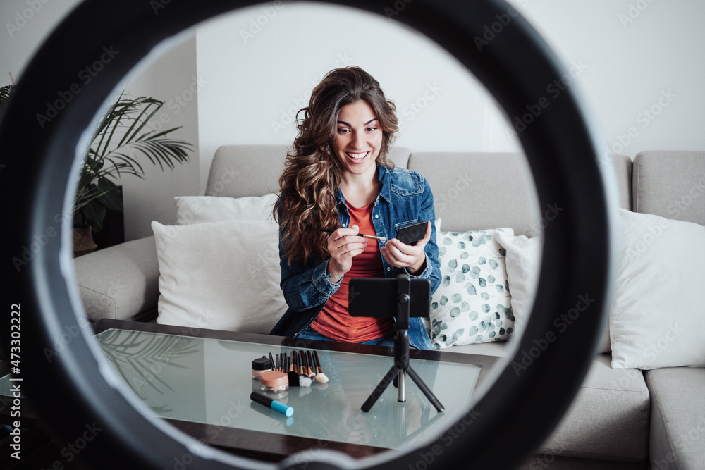 Smiling influencer with make-up palette influencing at home studio ...