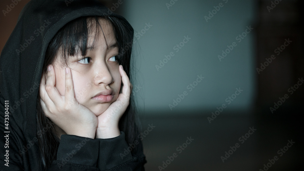 Sad lonely little girl crying while sitting in dark room with an ...