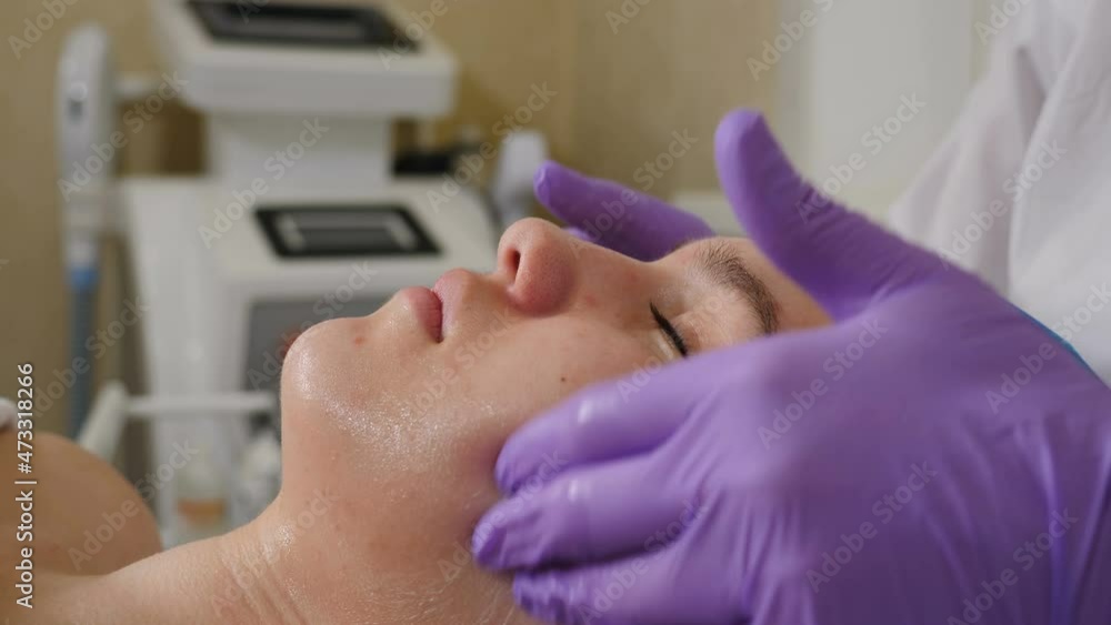 Beautician applying acid peeling solution on female client face rubbing ...