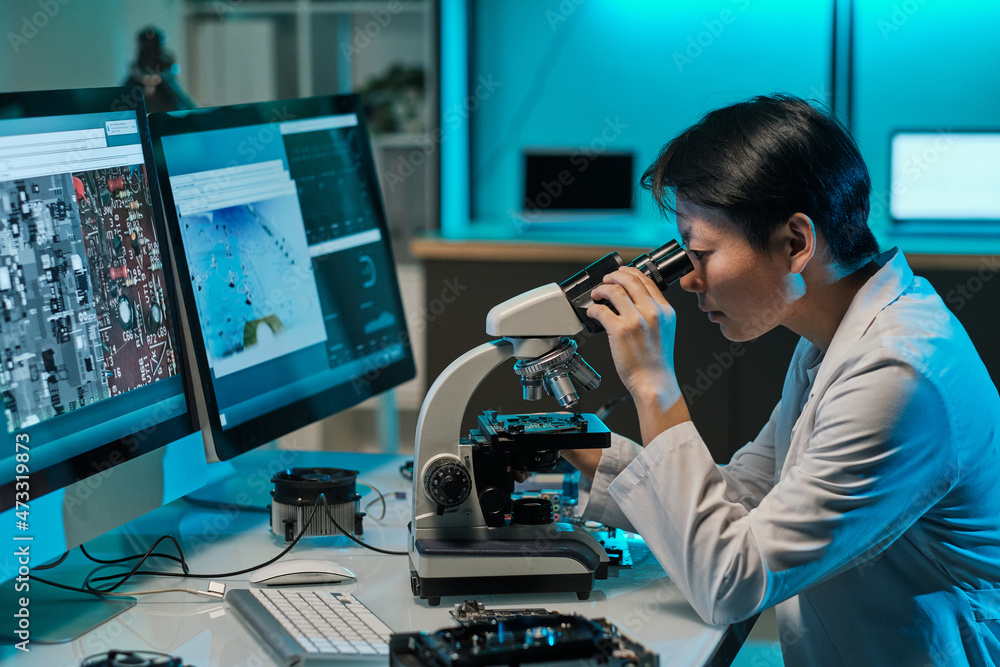 Asian female scientist looking in microscope during scientific ...