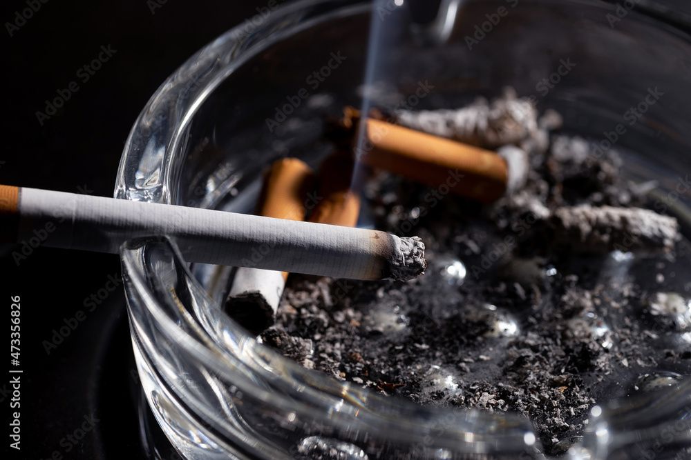 Ashtray and smoking cigarette on black background Stock Photo | Adobe Stock