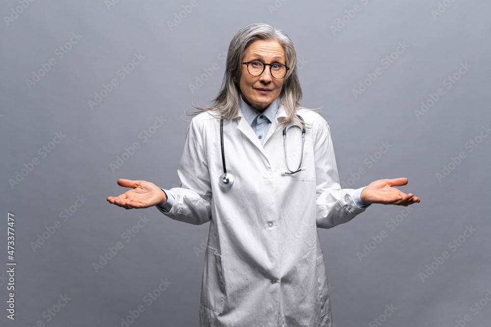 Confused and puzzled mature female physician in medical gown with a ...
