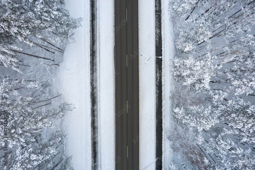 Aerial view of asphalt highway leading through frosty winter forests ...