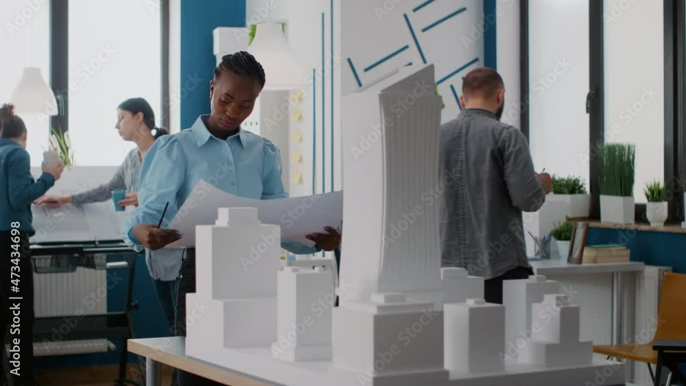Portrait of african american architect looking at blueprints plans to ...