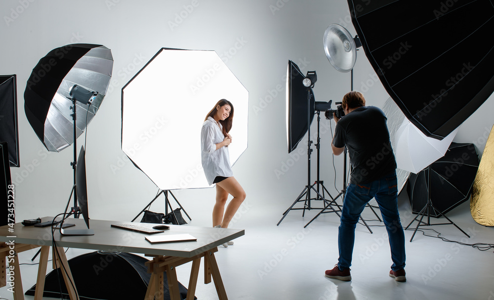 Photographer and pretty model working in modern lighting studio with ...
