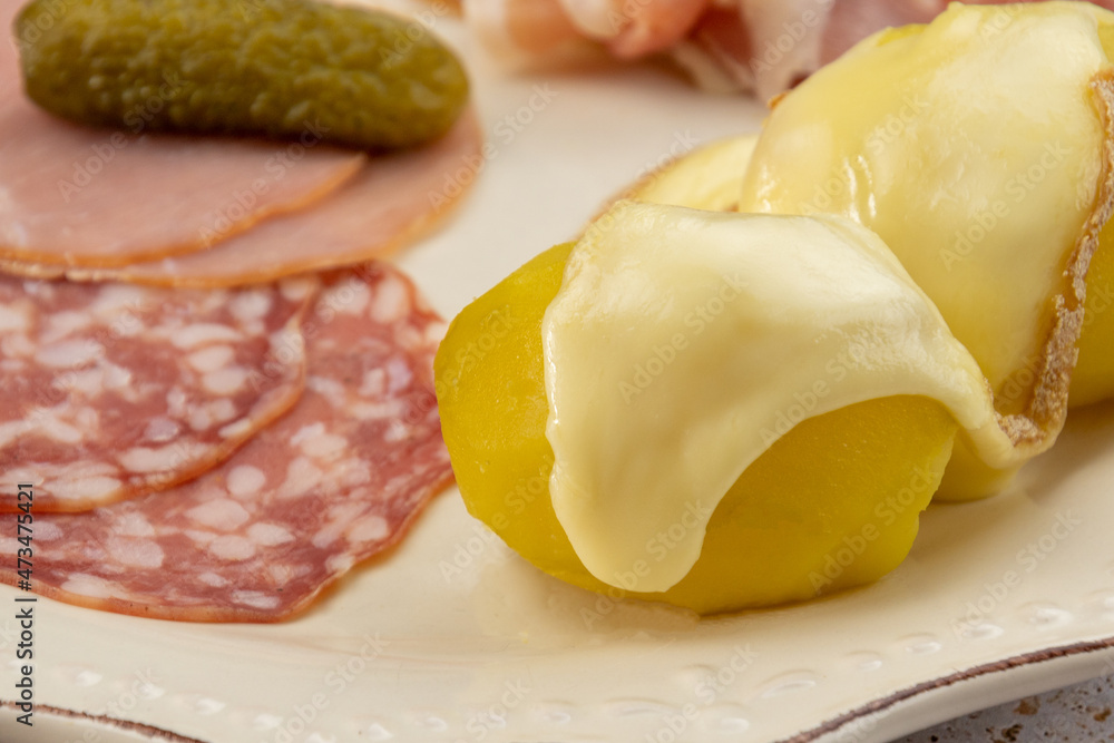 fromage à raclette fondu sur des pommes de terre et charcuterie dans ...