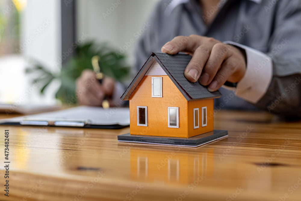 Salesman holding an orange model of a small house, a housing project ...