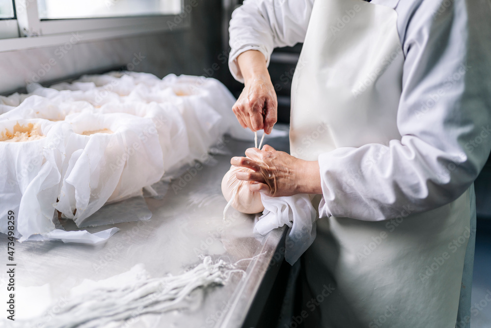 Skilled chef wrapping cheese in cloth at factory Stock Photo | Adobe Stock