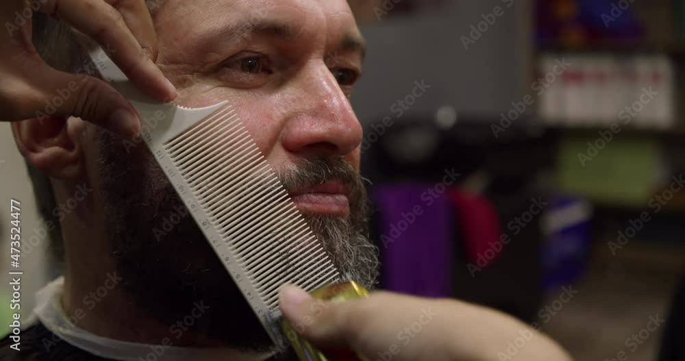 Beard cut with blade at barbershop, professional hairdresser shaves his ...