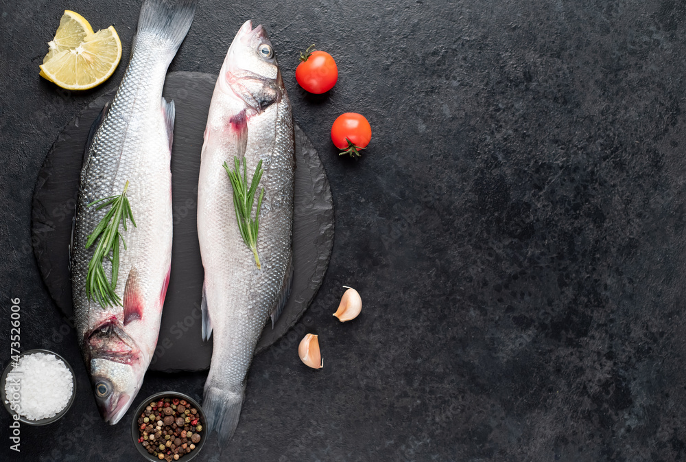 raw sea bass fish with spices on a stone background with copy space for ...