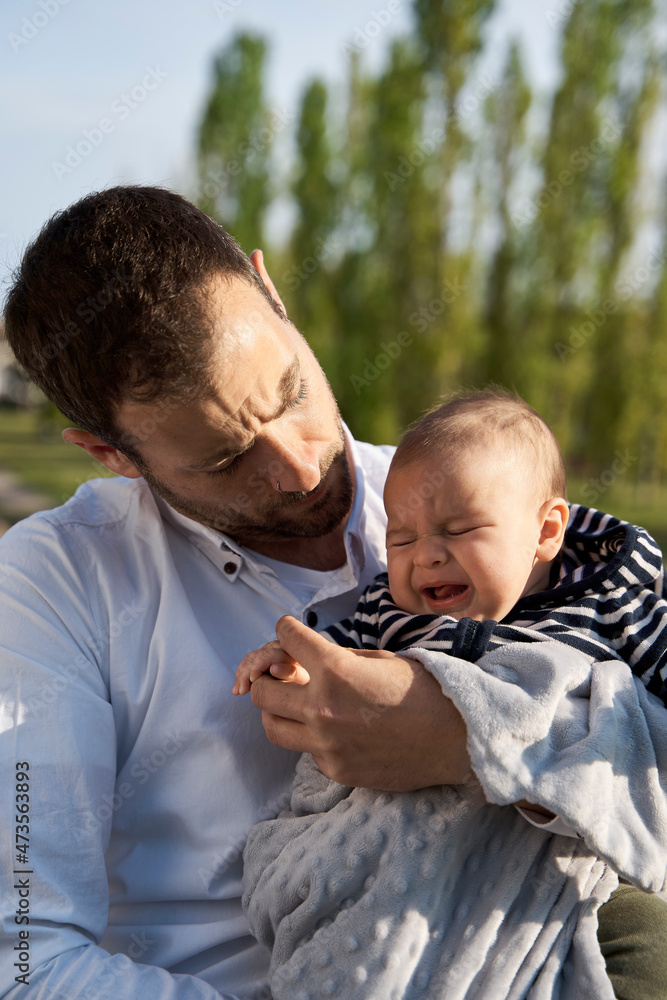 Father consoling baby boy crying at park Stock Photo | Adobe Stock