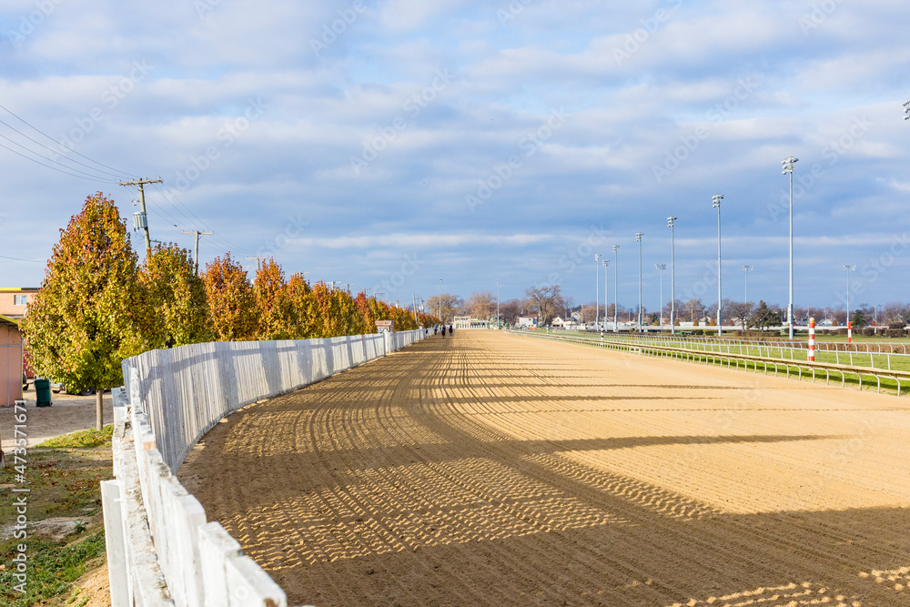 A fall day on an empty horse racetrack looking down the dirt track with ...
