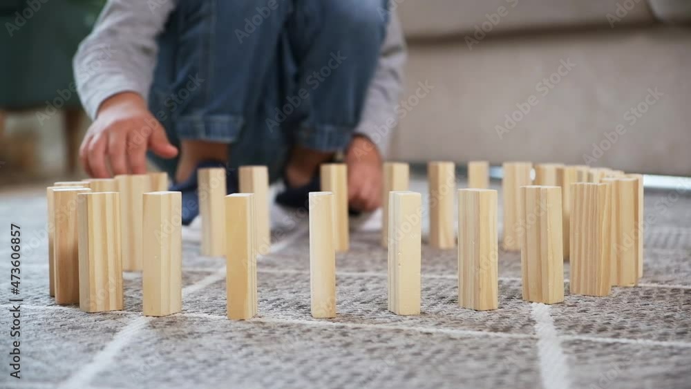 Child pushing wooden block and starting domino effect. Wooden blocks ...