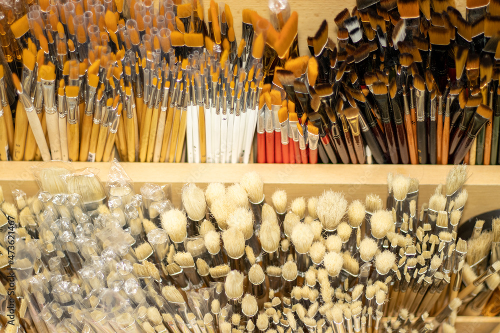 stack of paint brushes in an art store on wooden shelves. natural or ...