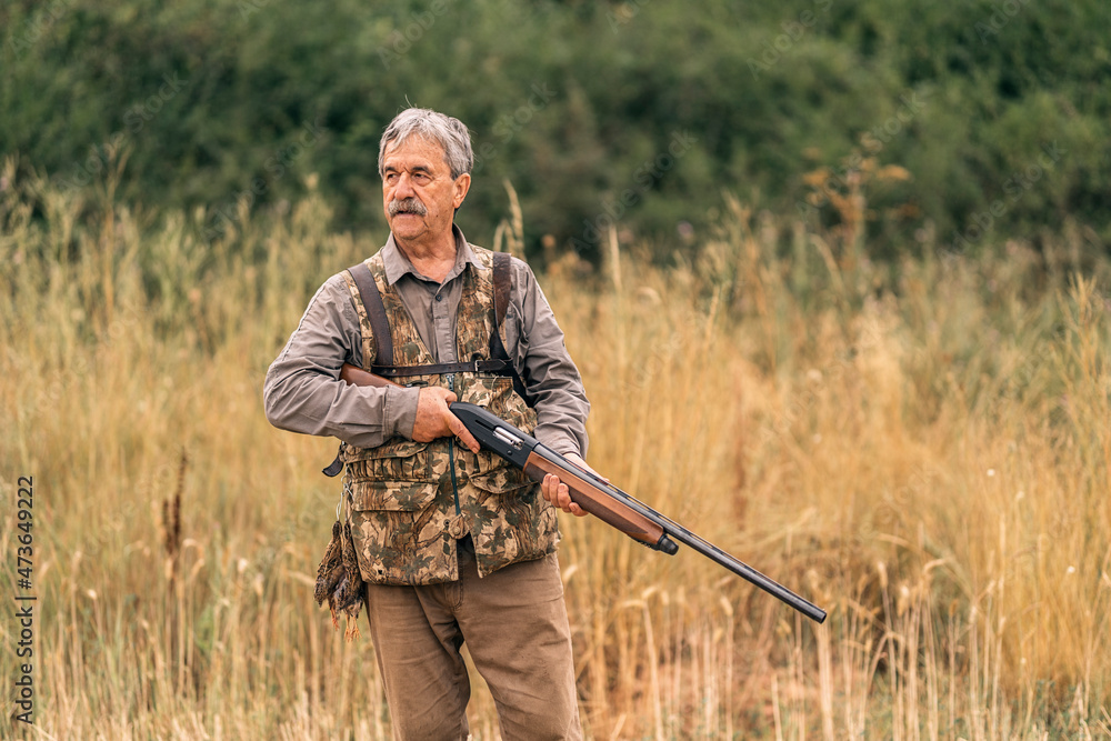 Mature hunting man holding a gun while searching for new preys. Stock ...