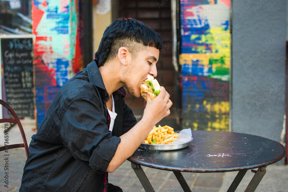 Gen Z trans man eating a burger Stock Photo | Adobe Stock