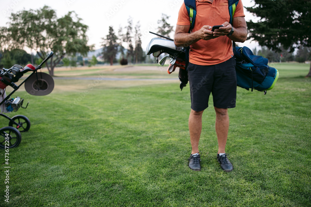 Golfer using mobile phone on golf course Stock Photo | Adobe Stock