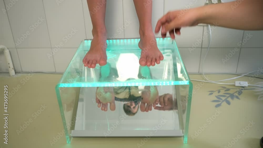 An orthopedic doctor examines the boy's feet on a plantograph, legs ...
