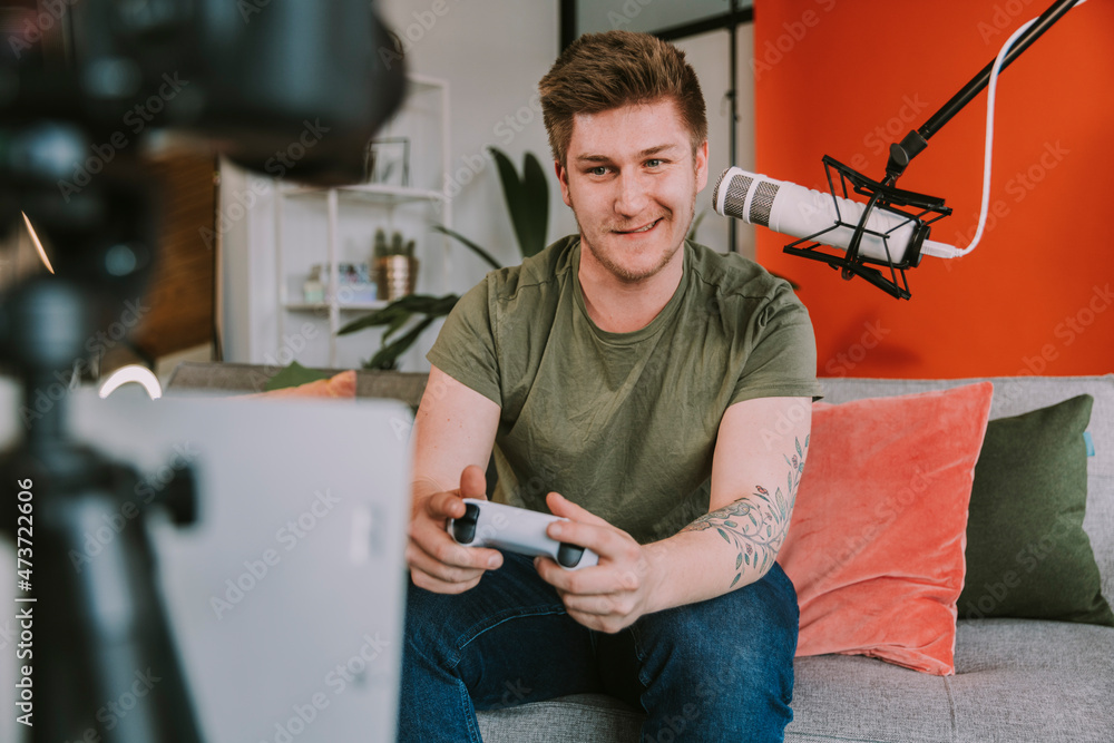 Male gamer playing video game while vlogging at home Stock Photo ...