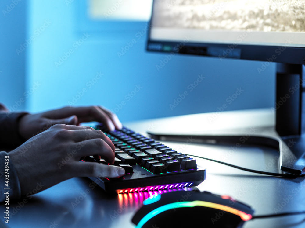Teenage boy playing video game using keyboard on computer at table ...