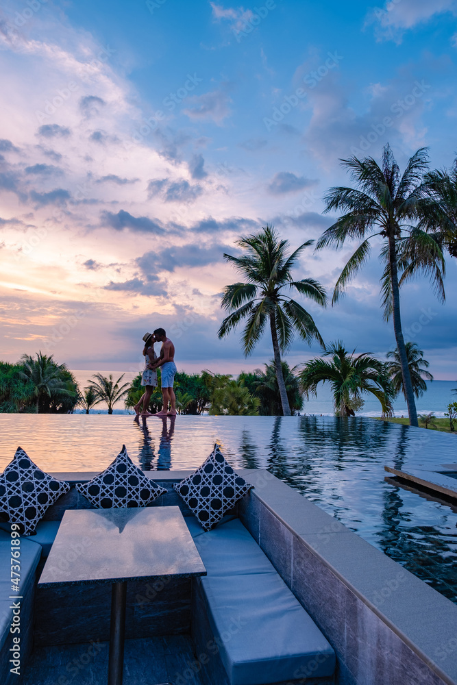 couple watching the sunset in an infinity pool on a luxury vacation in ...