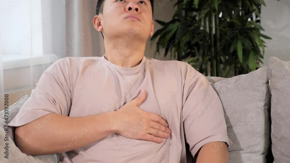 Trouble breathing, chest pain, chinese man sitting on couch at home ...