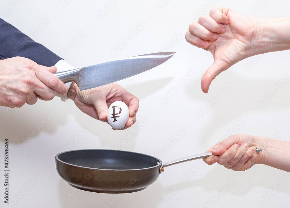 A man holds an egg with the symbol of the Russian ruble in his hands ...