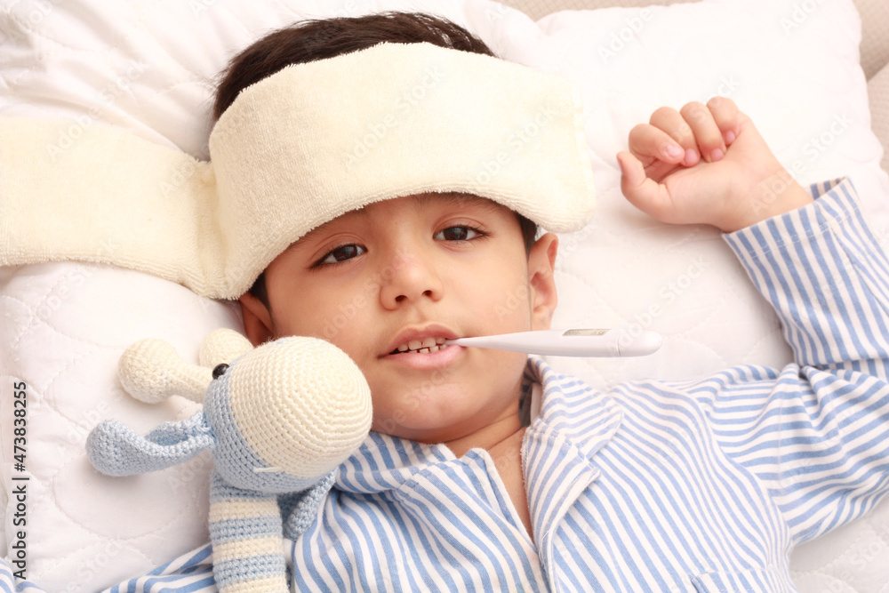 Sick boy with thermometer laying in bed. Sick child with fever and ...