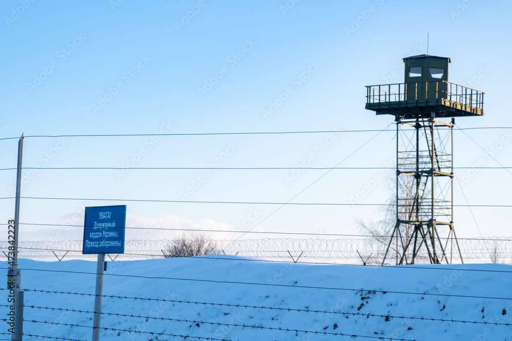Surveillance tower, iron fence and caution banner with an inscription ...