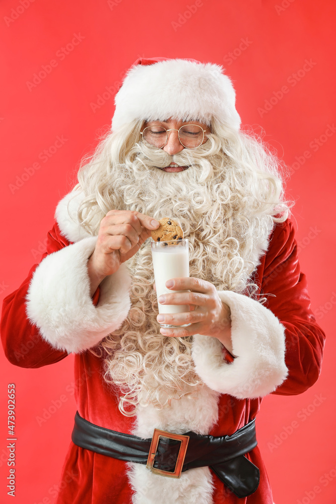Santa Claus with tasty cookie and glass of milk on color background ...