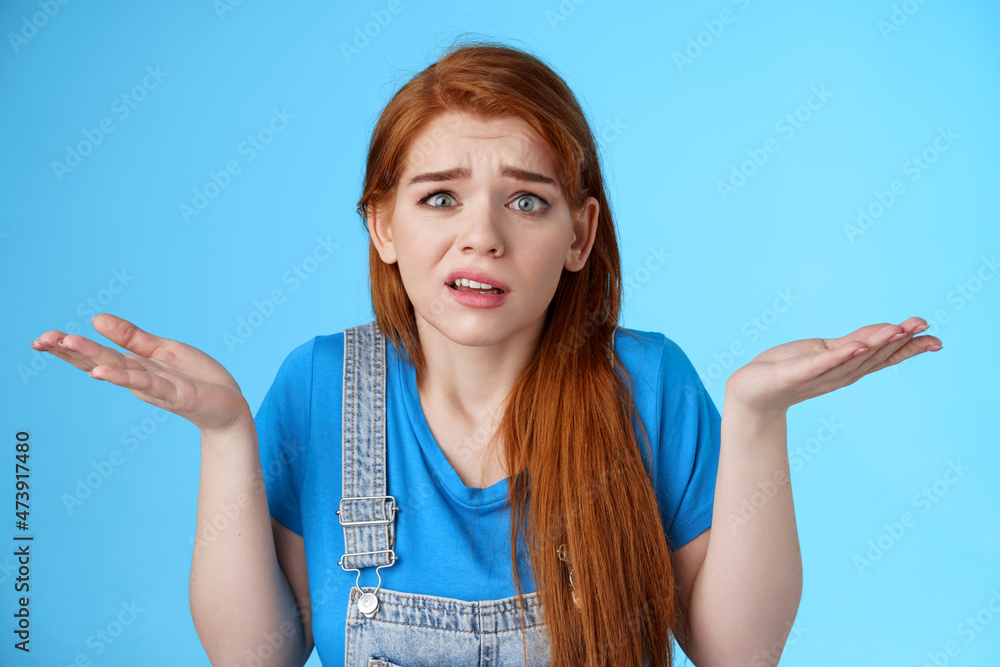 Perplexed uneasy stupified worried redhead woman shrugging, have no ...