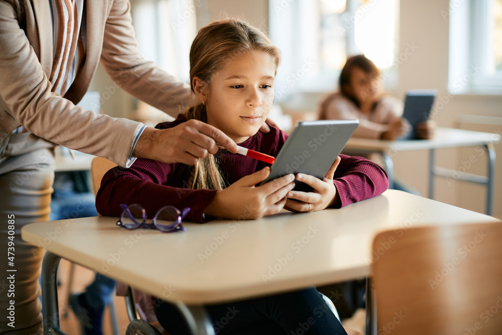 Little girl uses touchpad with teacher's assistance during class at ...