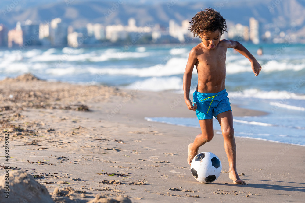 Shirtless boy playing with soccer ball at beach Stock Photo | Adobe Stock