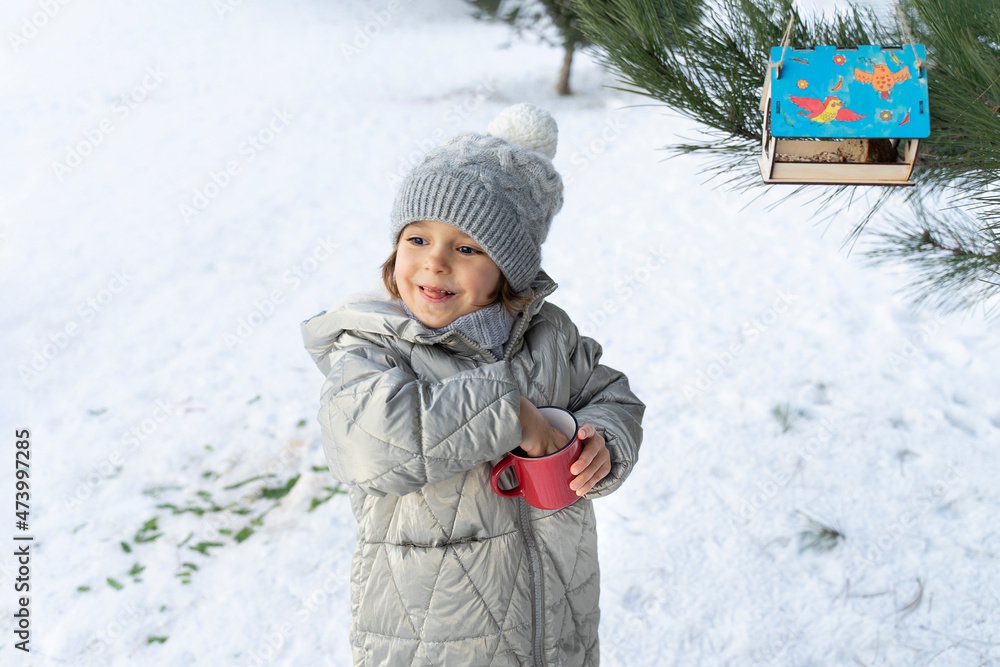Child girl feeding birds in winter. Bird feeder in snowy tree, helping ...
