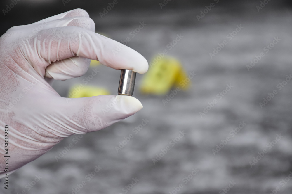 Forensic officer is holding handgun casings or pistol bullet which is ...