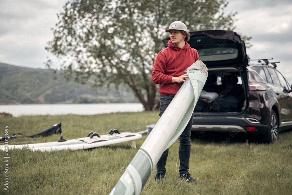 Windsurfer and camper packing and unpacking from a car's roof rack in ...