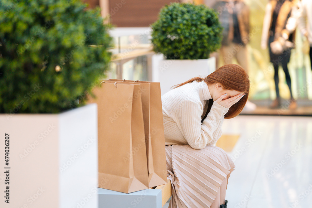 Sad exhausted young woman tired from shopping sitting on bench in mall ...