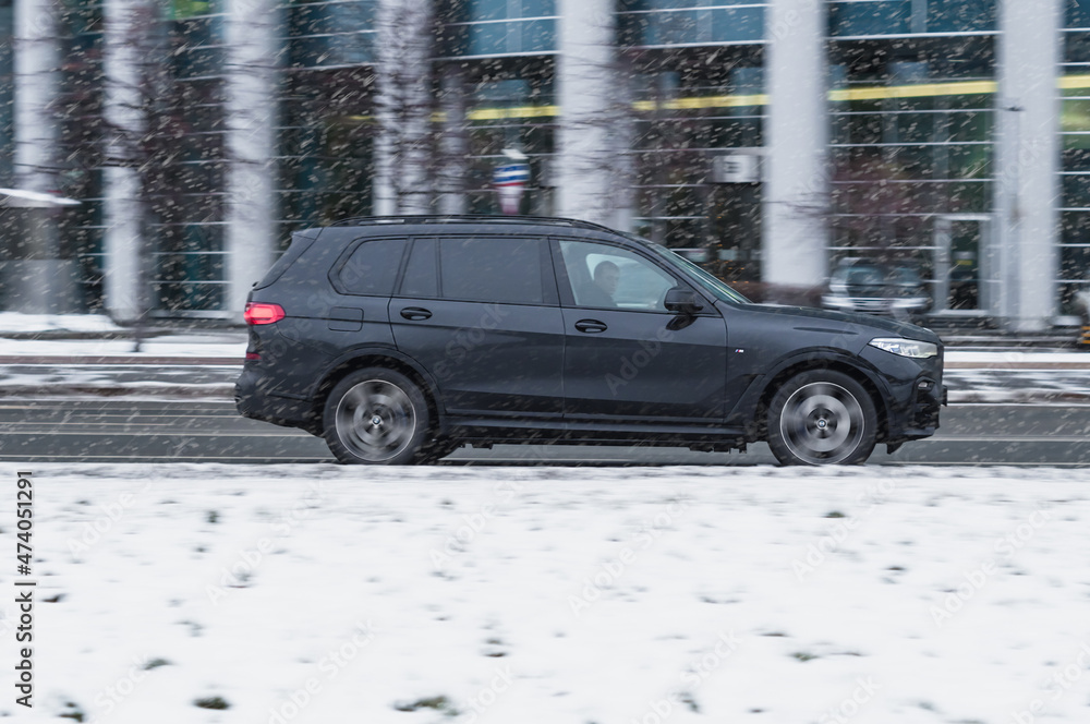 Fast moving BMW X7 on winter city road. Black SUV with man driving ...