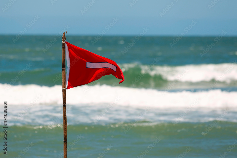 Red flag lifeguard danger warning sign on the beach. No swimming it's ...