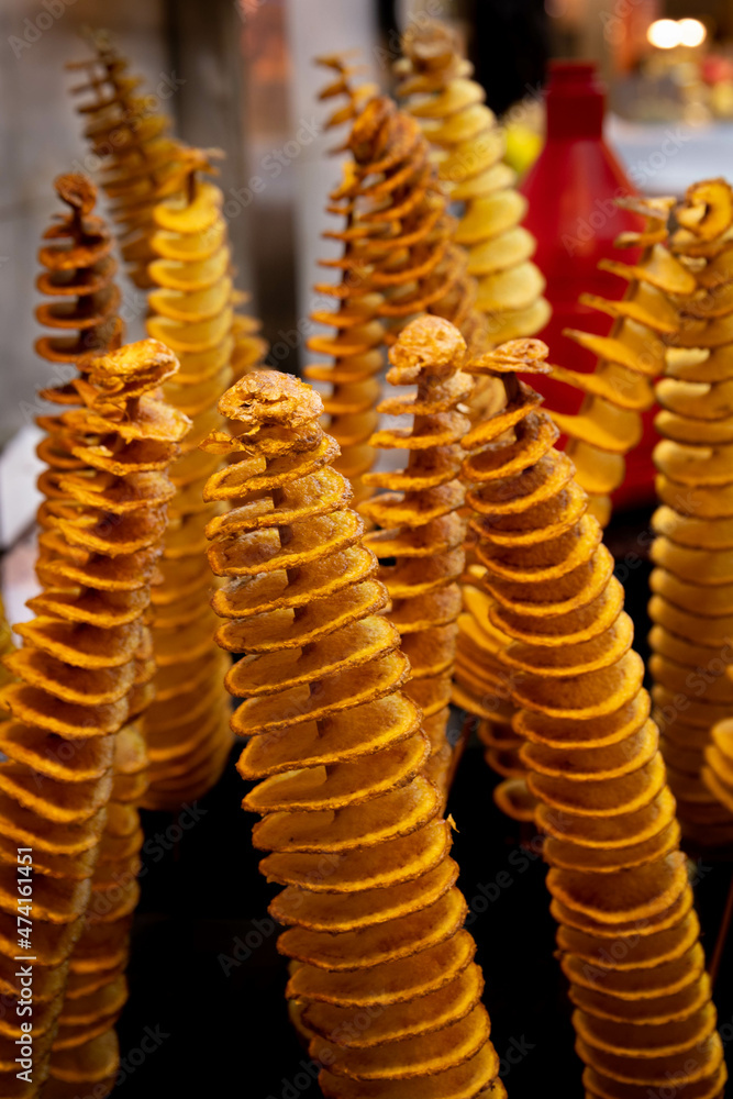 Twisted fried potato chips in a stick at the market. Unhealthy street ...