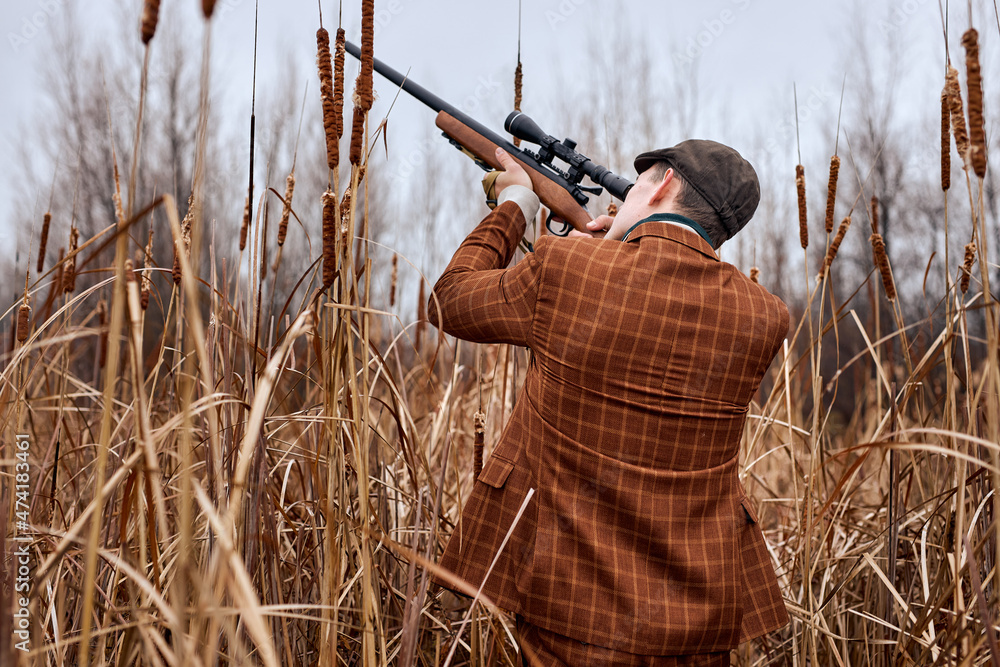 european handsome hunter is hunting in forest, looking through the ...
